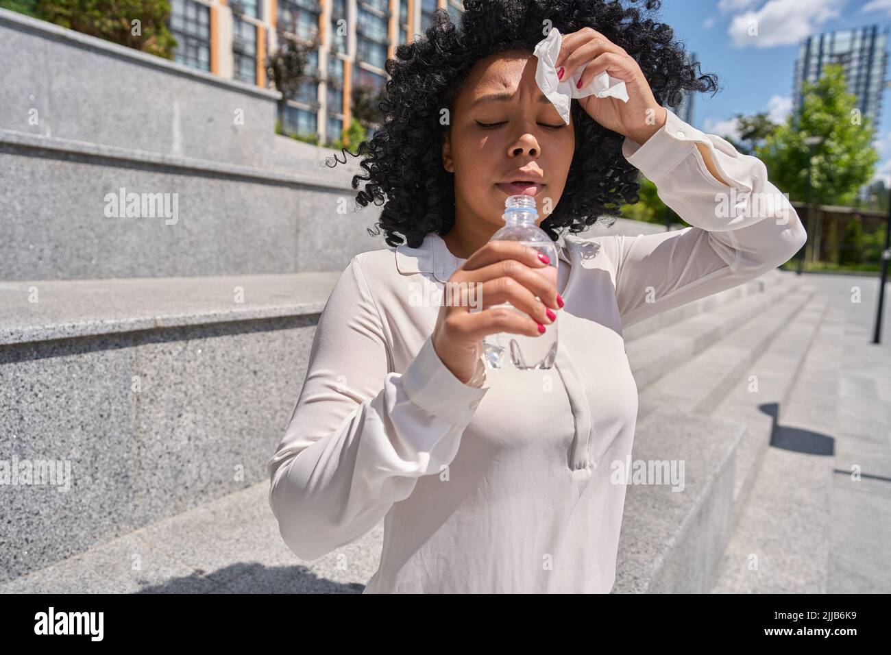 Multiracial woman drinking water in the scorching sun Stock Photo - Alamy
