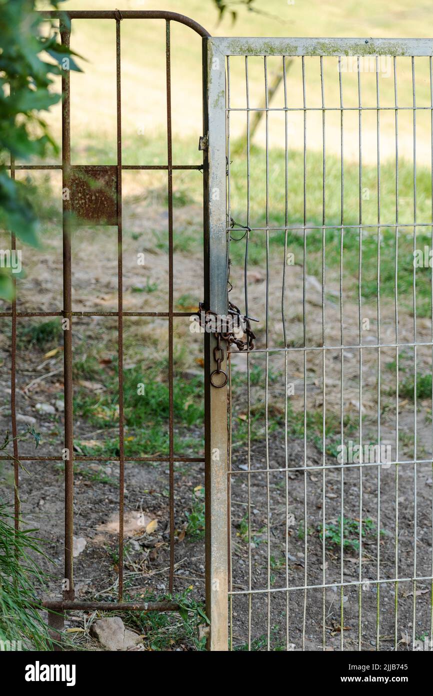 Closed lattice metal door with a chain on a farm pasture Stock Photo ...