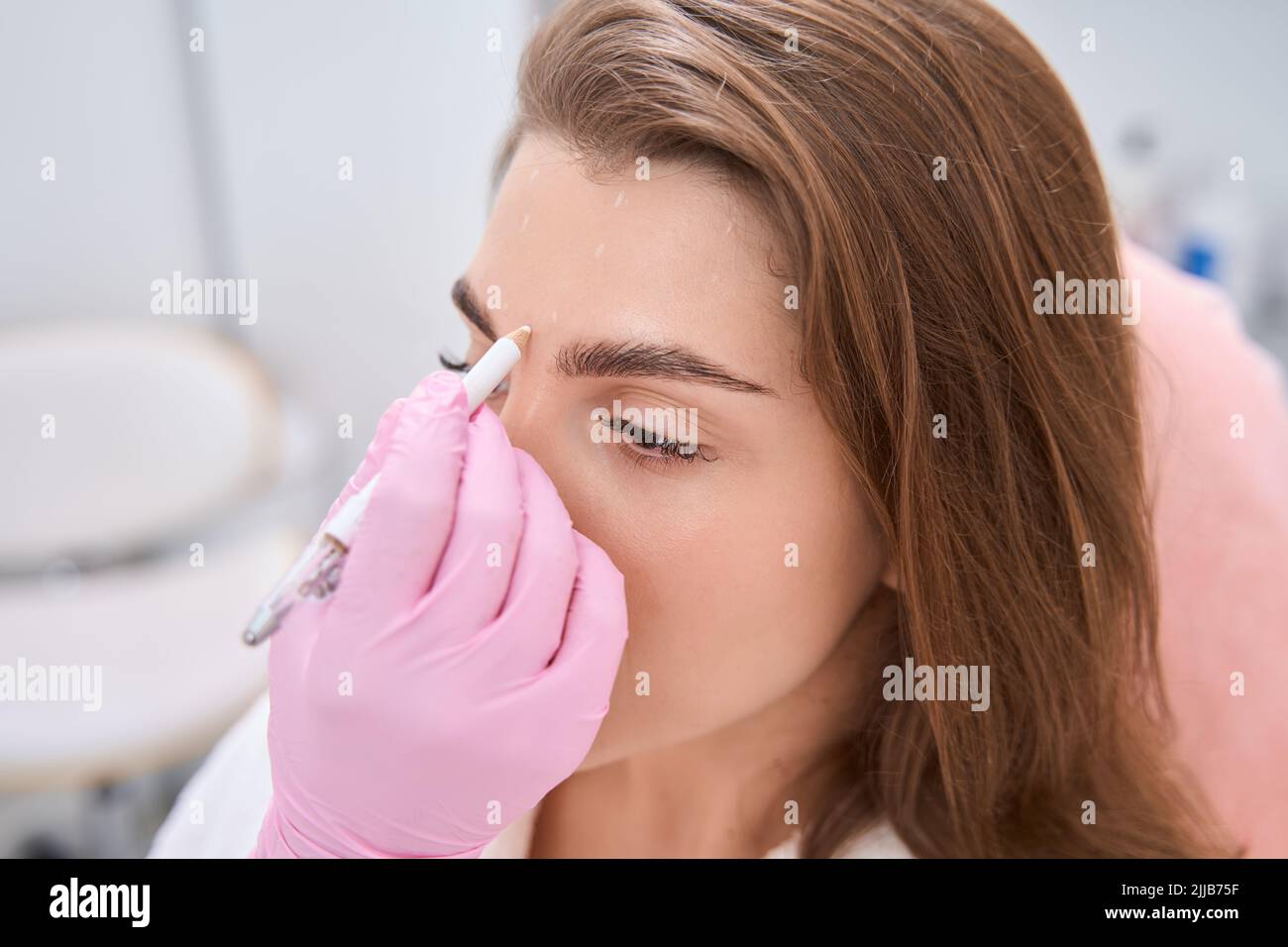 Lady puts a mark between eyebrows on face of patient Stock Photo - Alamy