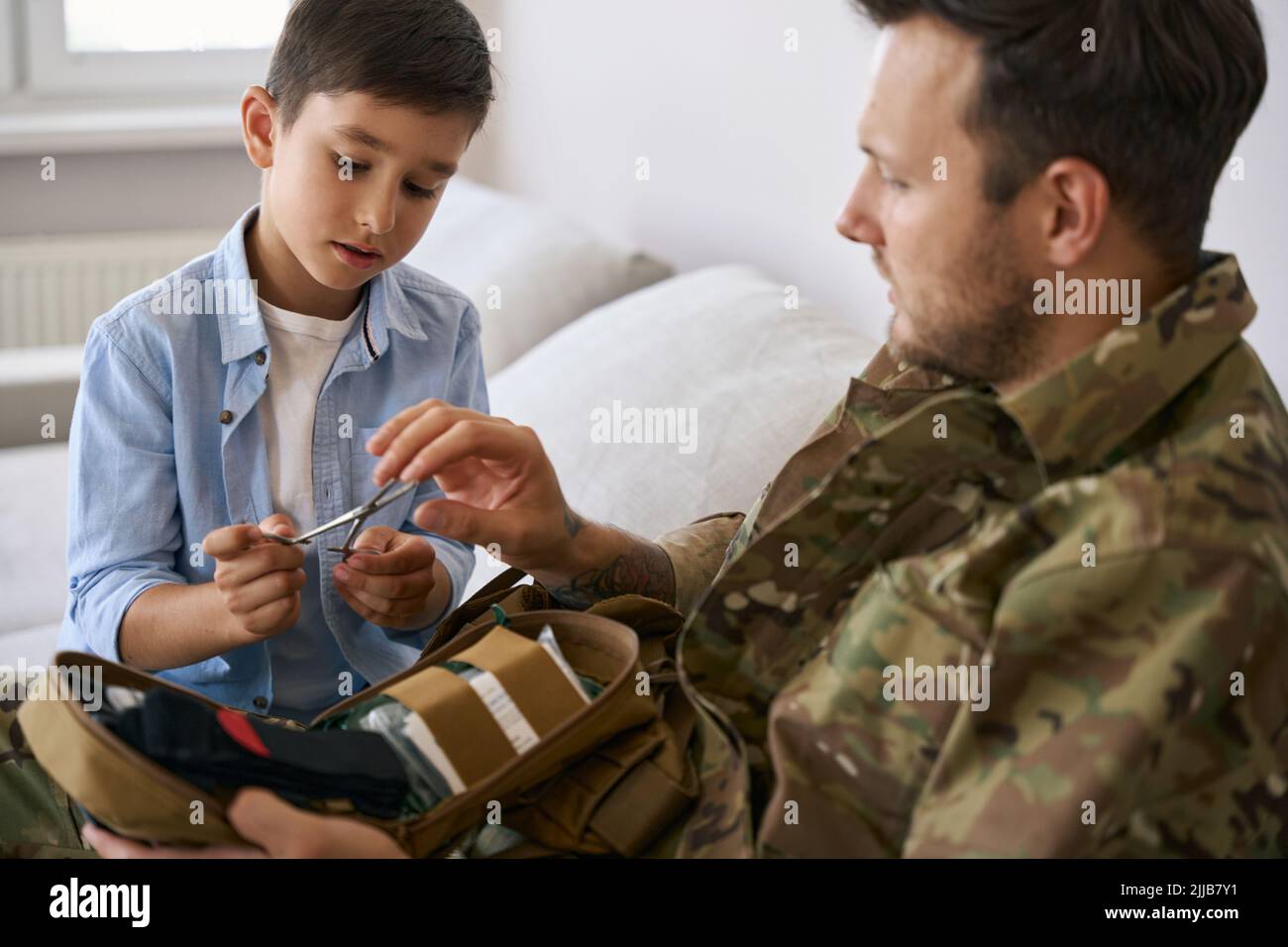 Military man teaching kid to use medical scissors Stock Photo - Alamy