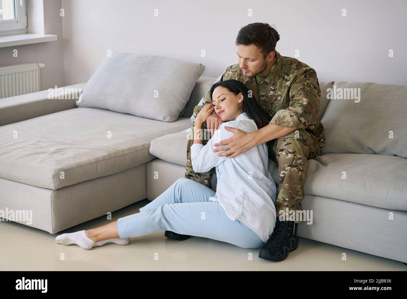 Army man on sofa hugging wife near his leg Stock Photo - Alamy