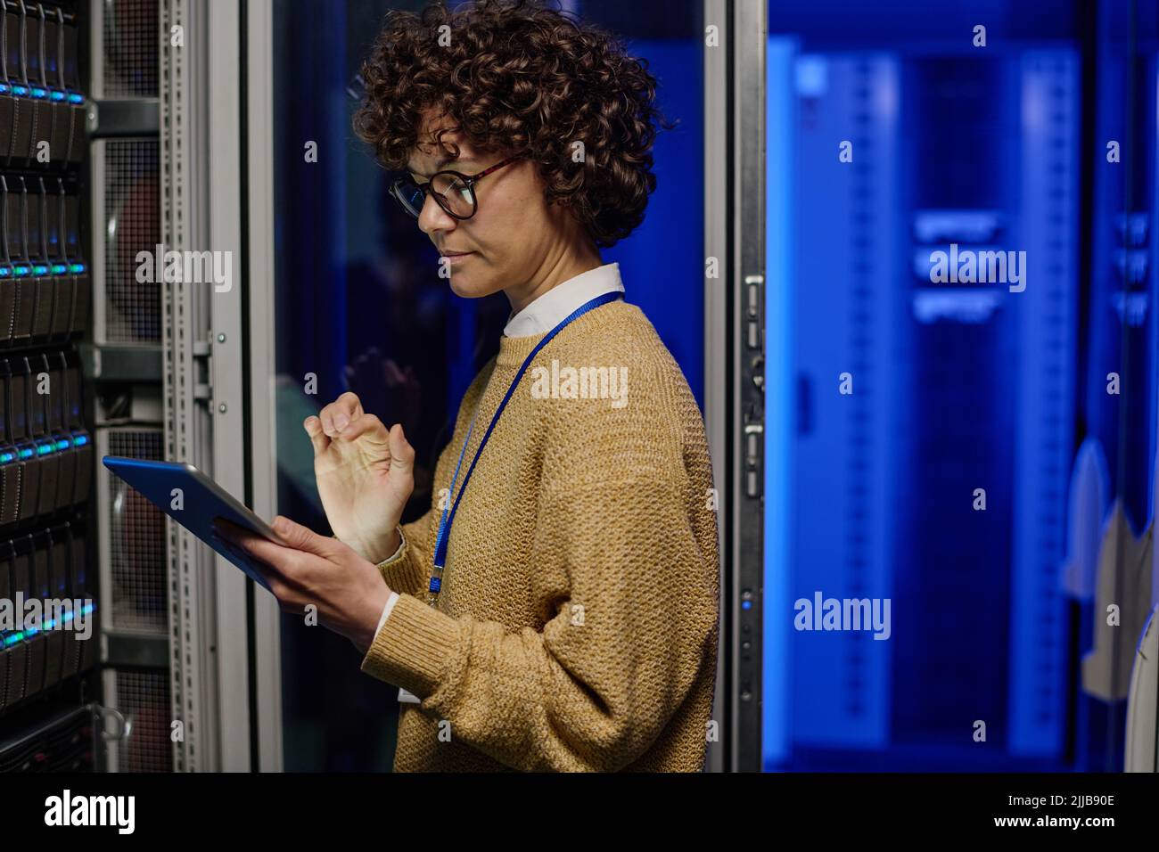 Female engineer opening server rack and checking the work of computer ...