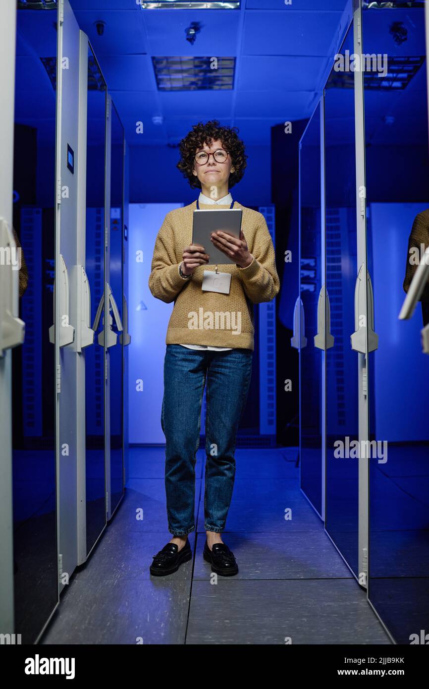 Female engineer standing at server rack cabinet and using tablet pc for ...