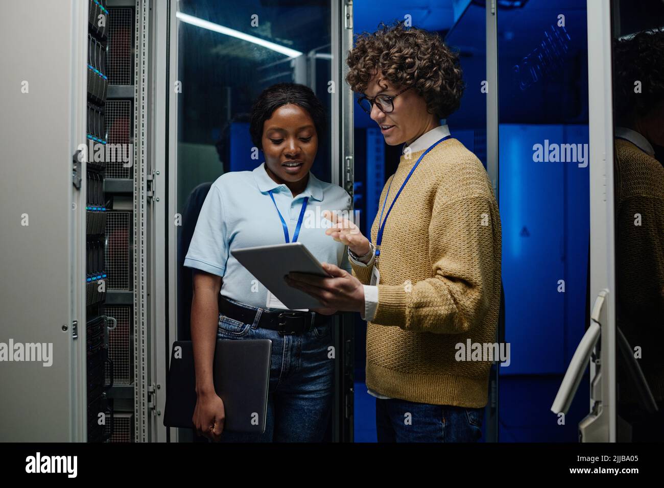 IT engineers standing beside server rack cabinet, doing wireless ...