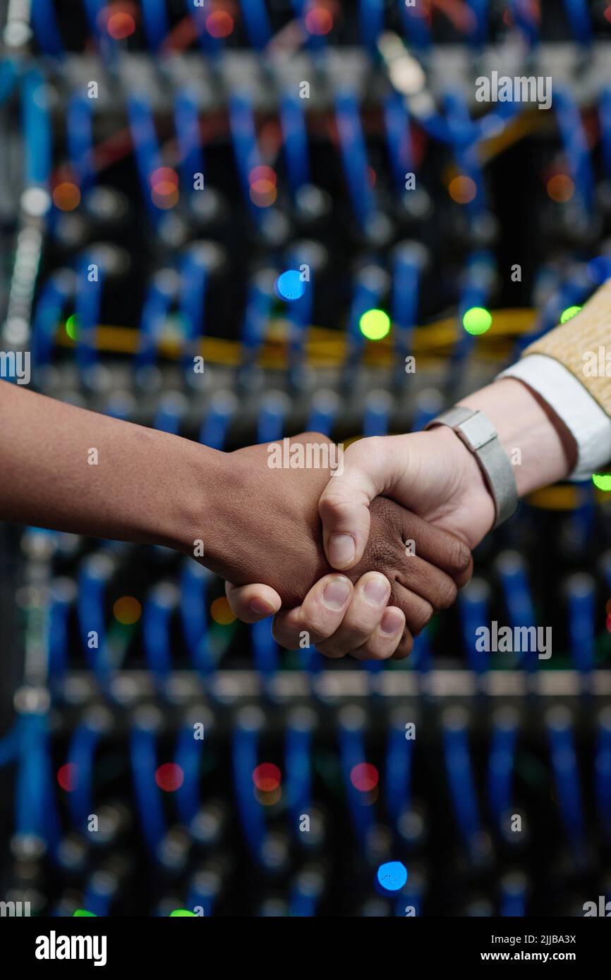 Close-up of server engineers shaking hands during teamwork in server ...