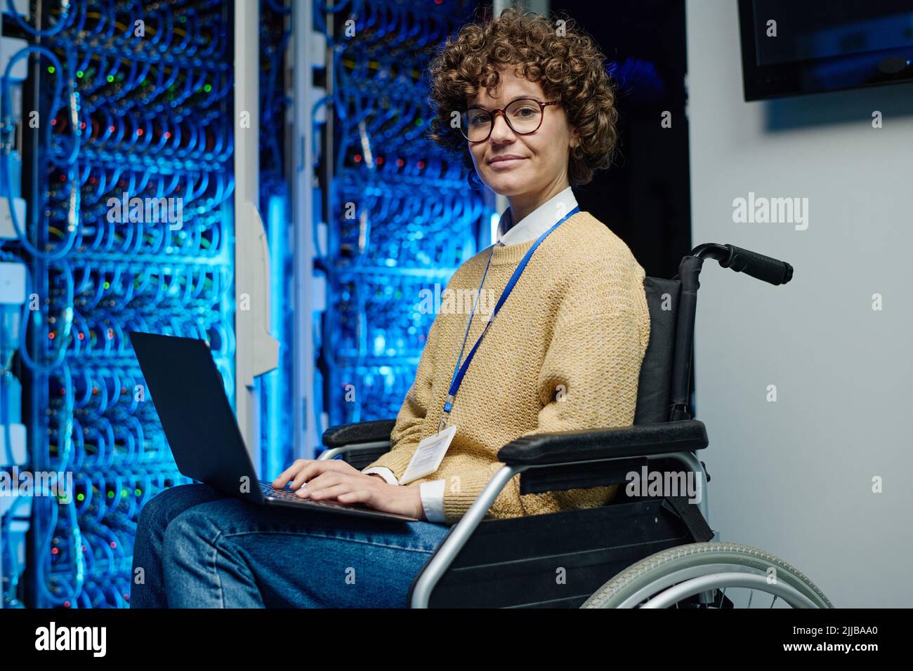 Portrait of IT female engineer sitting in wheelchair and working on laptop online managing ...