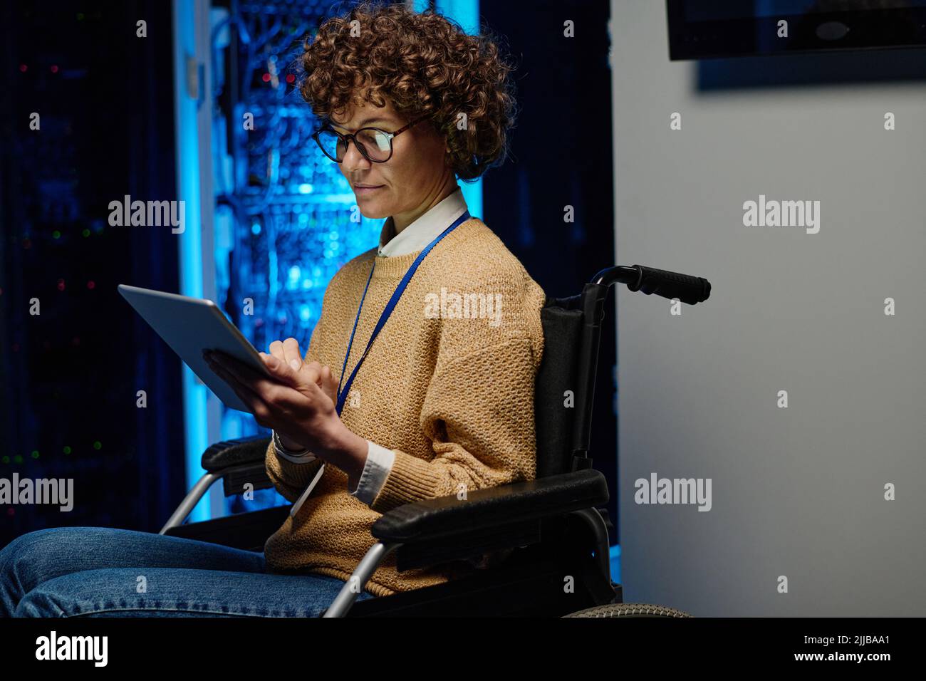 Female IT engineer typing information on digital tablet sitting in wheelchair, she working in ...