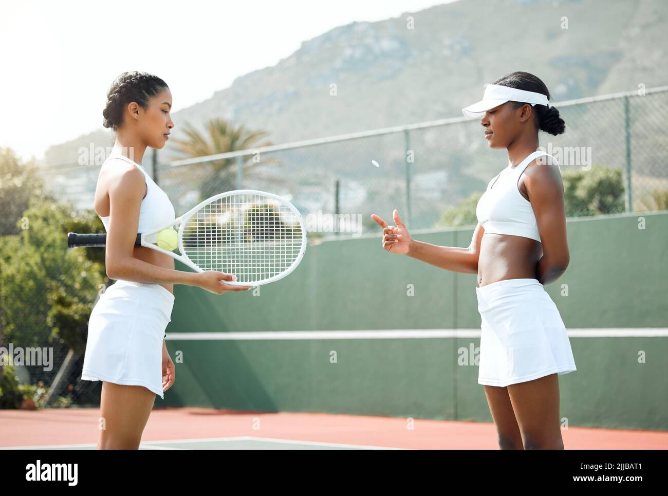 What will the outcome be. two sporty young women flipping a coin before ...