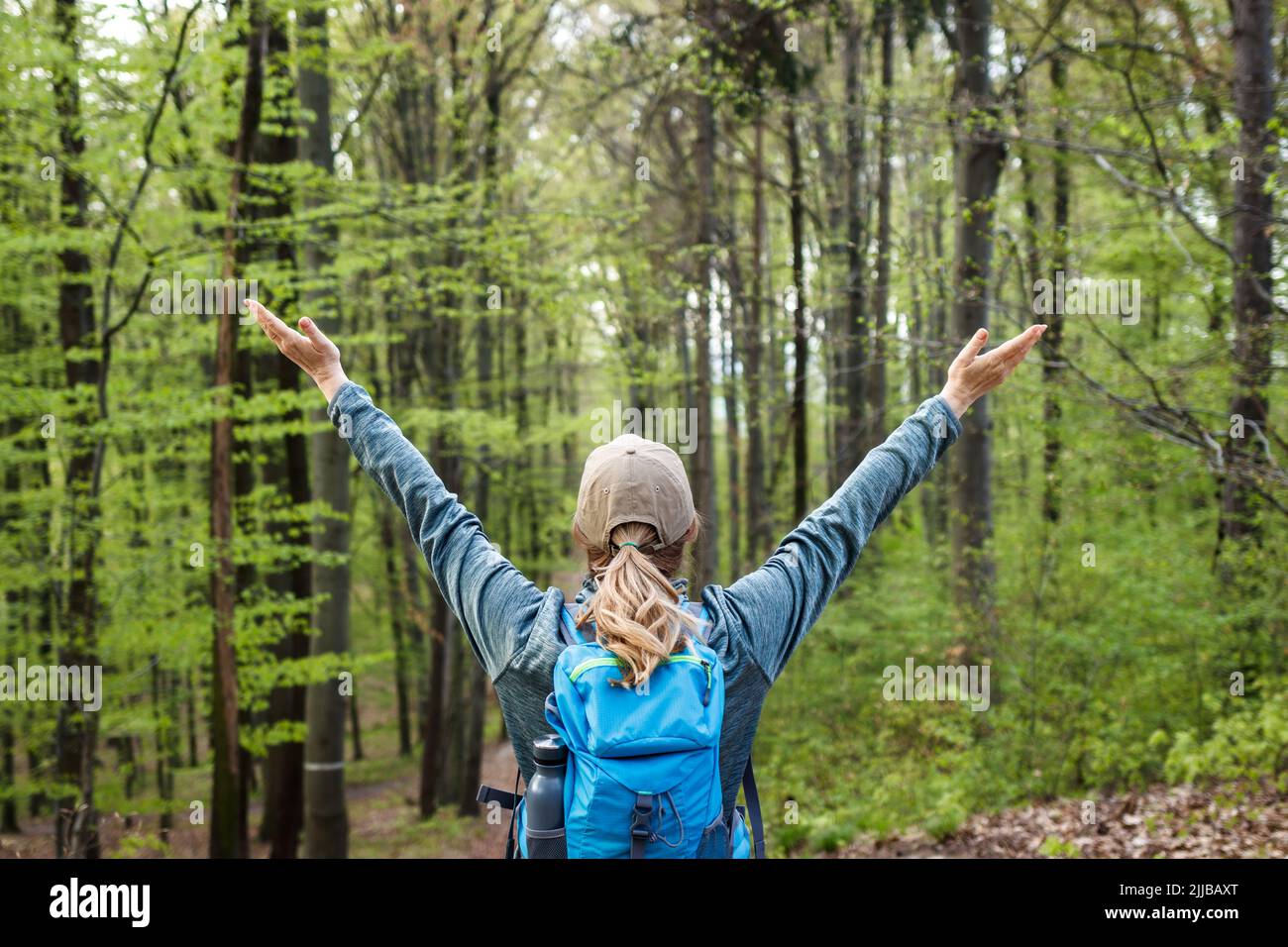 Happy woman enjoying hiking in forest. Female tourist with backpack ...