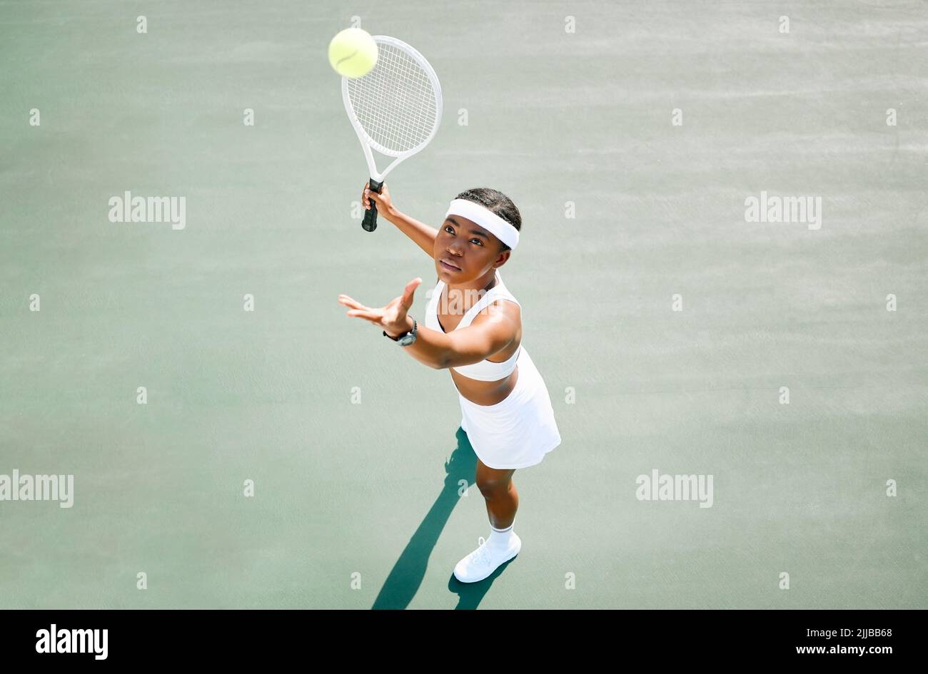 Theres power in her swing. a young woman serving a ball while playing ...