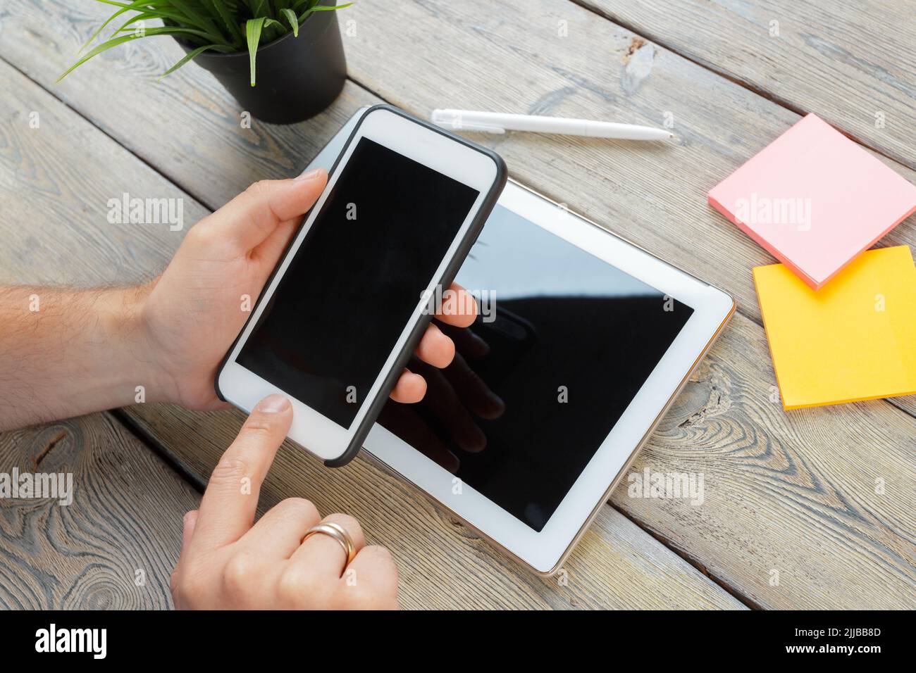 hands of a man holding tablet device over a wooden workspace table ...