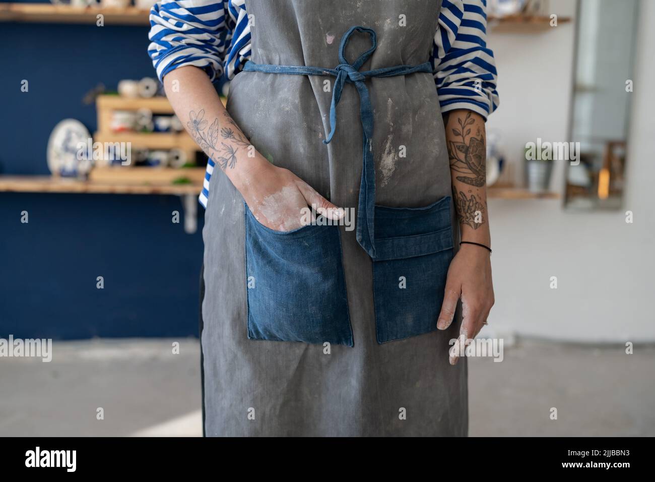 Female ceramist put hand at pocket after working with raw clay in ...