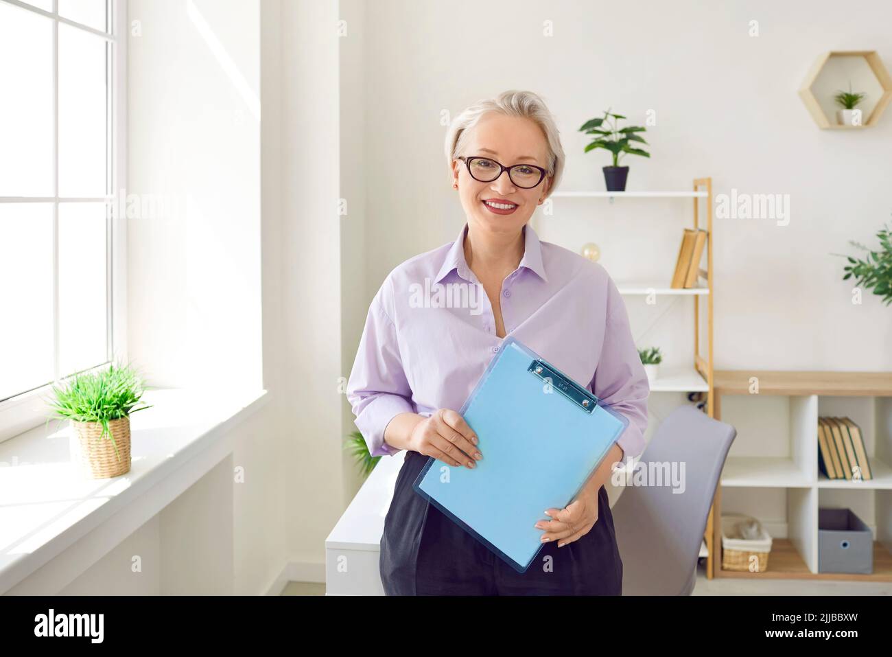 Office portrait of successful middle-aged business woman who is team ...