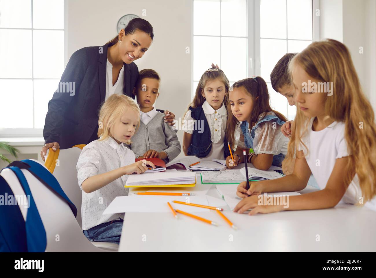 Group of first graders learn to write and read under guidance of ...