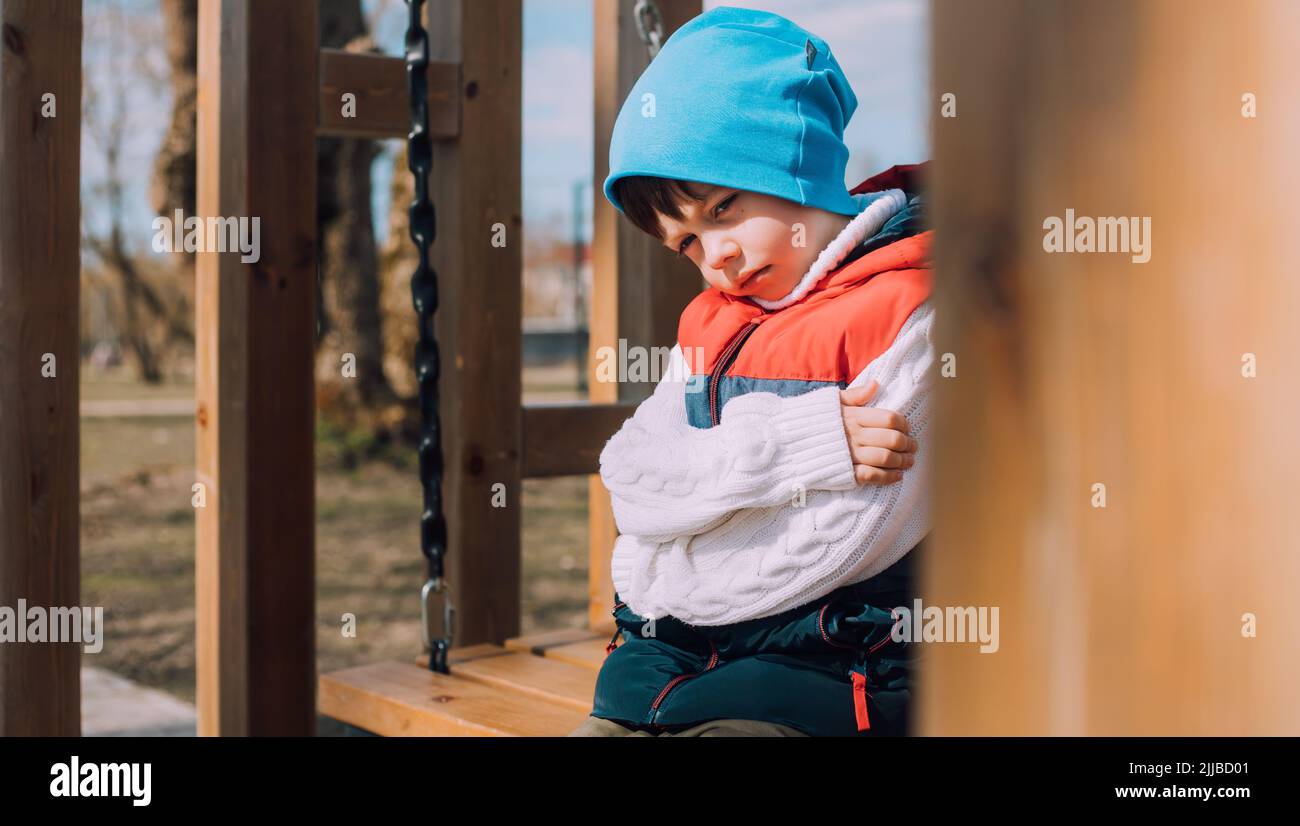 The offended boy is sitting on a lifestyle bench . Childish grievances ...