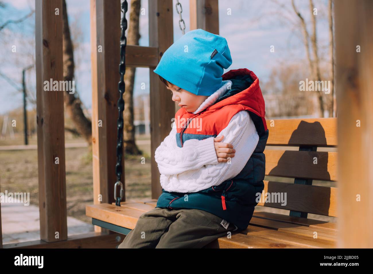The offended boy is sitting on a lifestyle bench . Childish grievances ...