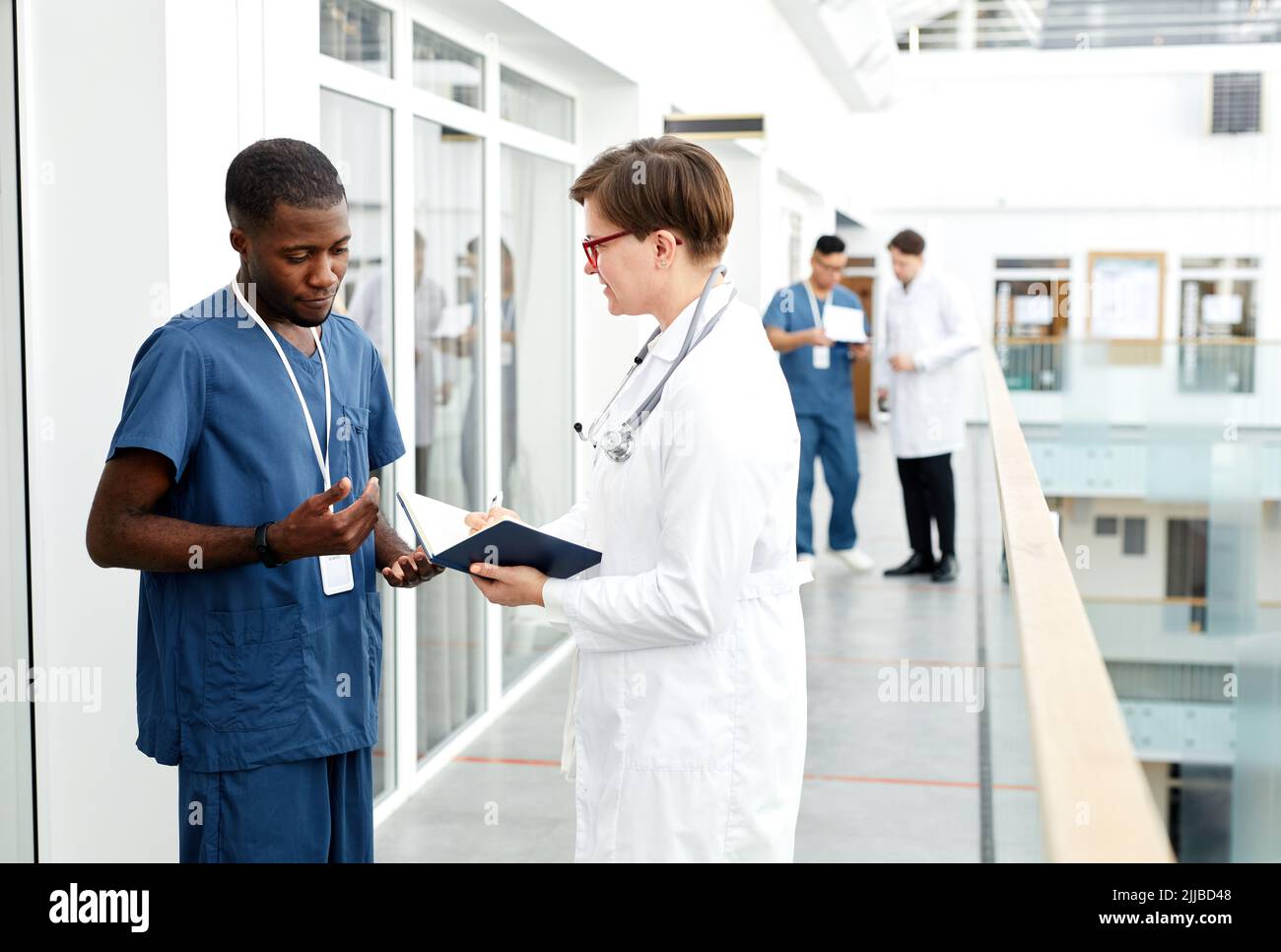 Side view portrait of female doctor talking to assistant while standing ...