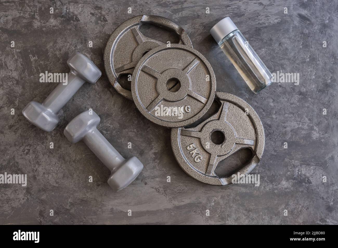Weight plates for barbell , dumbbells and water bottle in cement floor ...