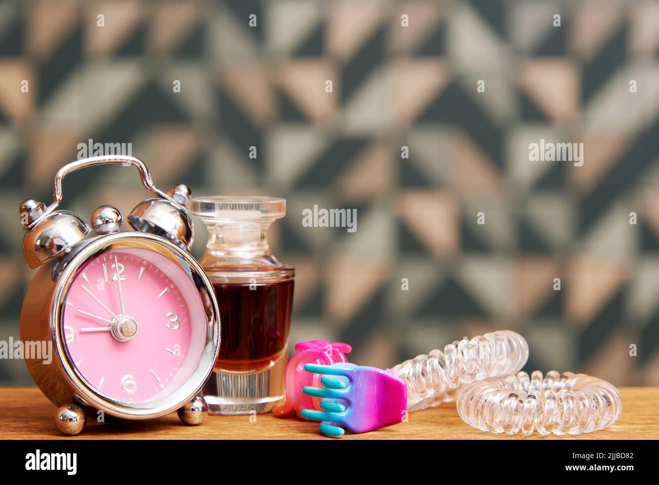 Small fancy alarm clock, perfume bottle with girly hairpins on the bed ...