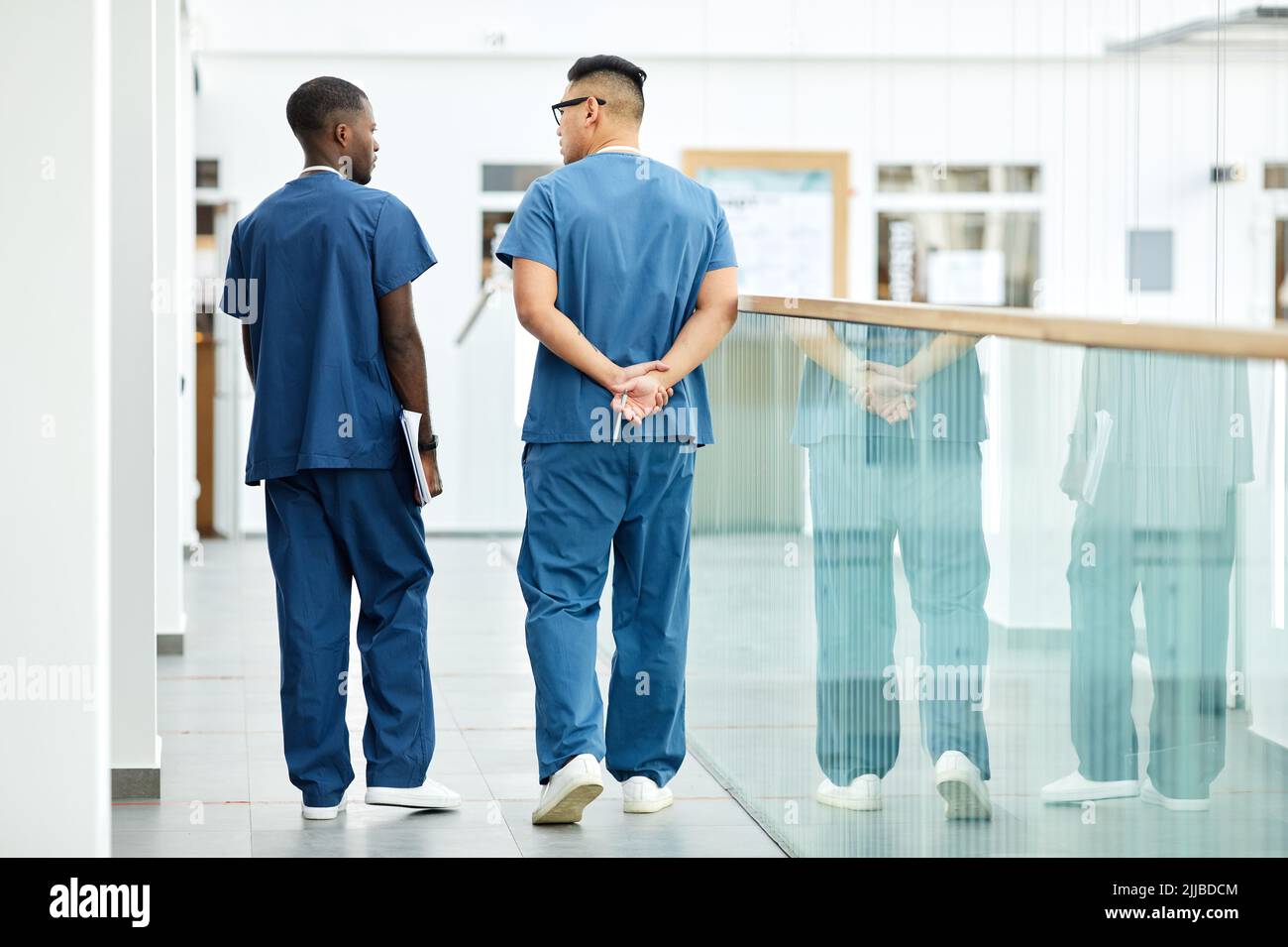 Back view full length of two doctors wearing blue uniform walking in ...