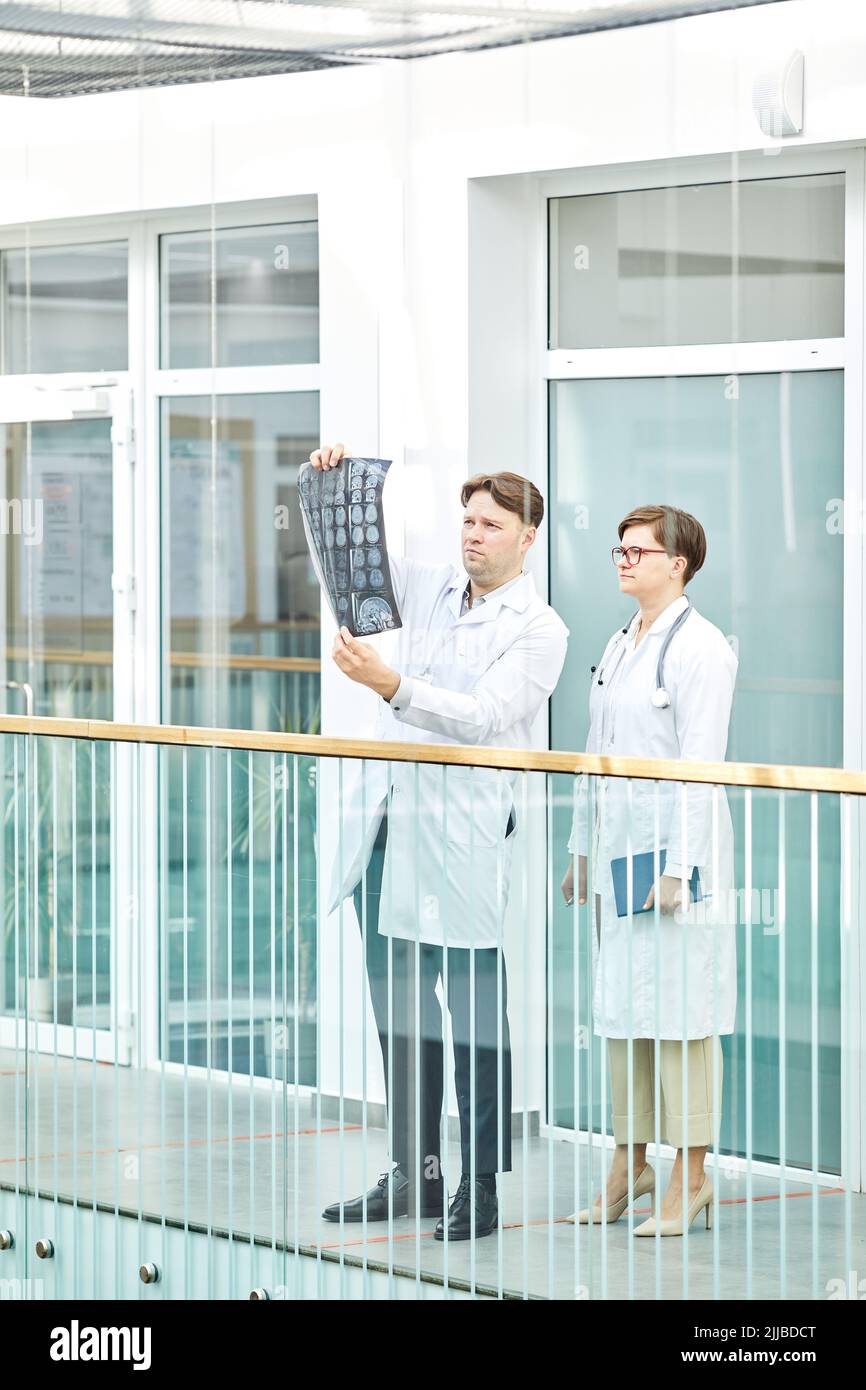 Vertical full length portrait of two expert doctors looking at x ray ...
