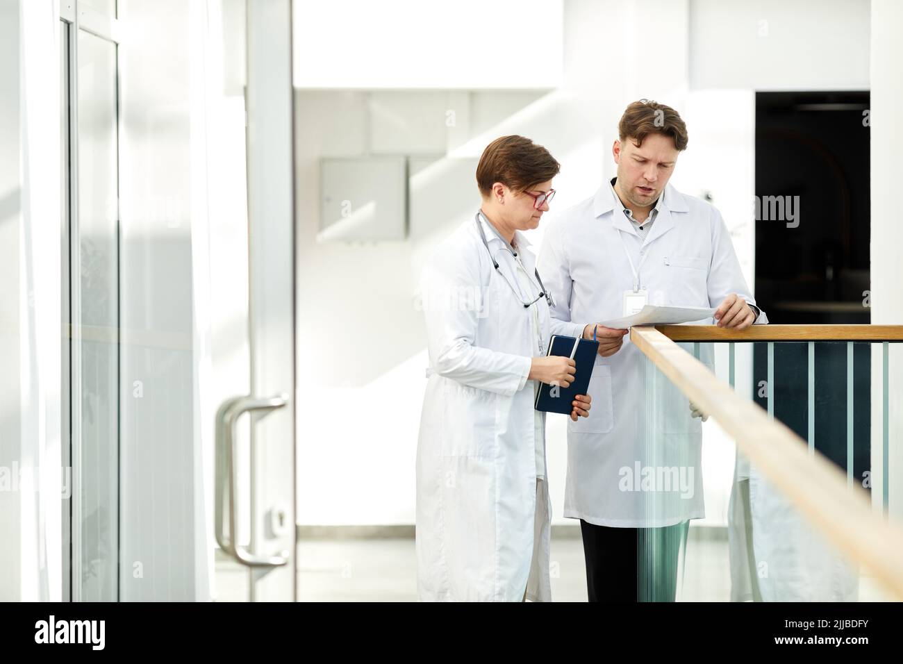 Minimal portrait of two expert doctors discussing case in hall of ...