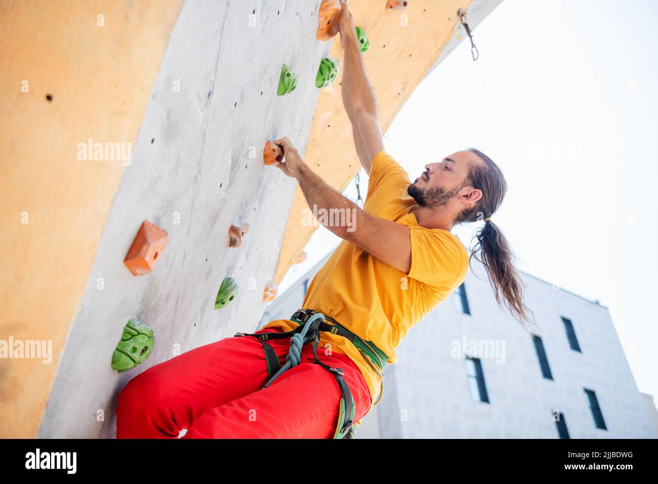 Man climber on artificial climbing wall outdoors against the background ...