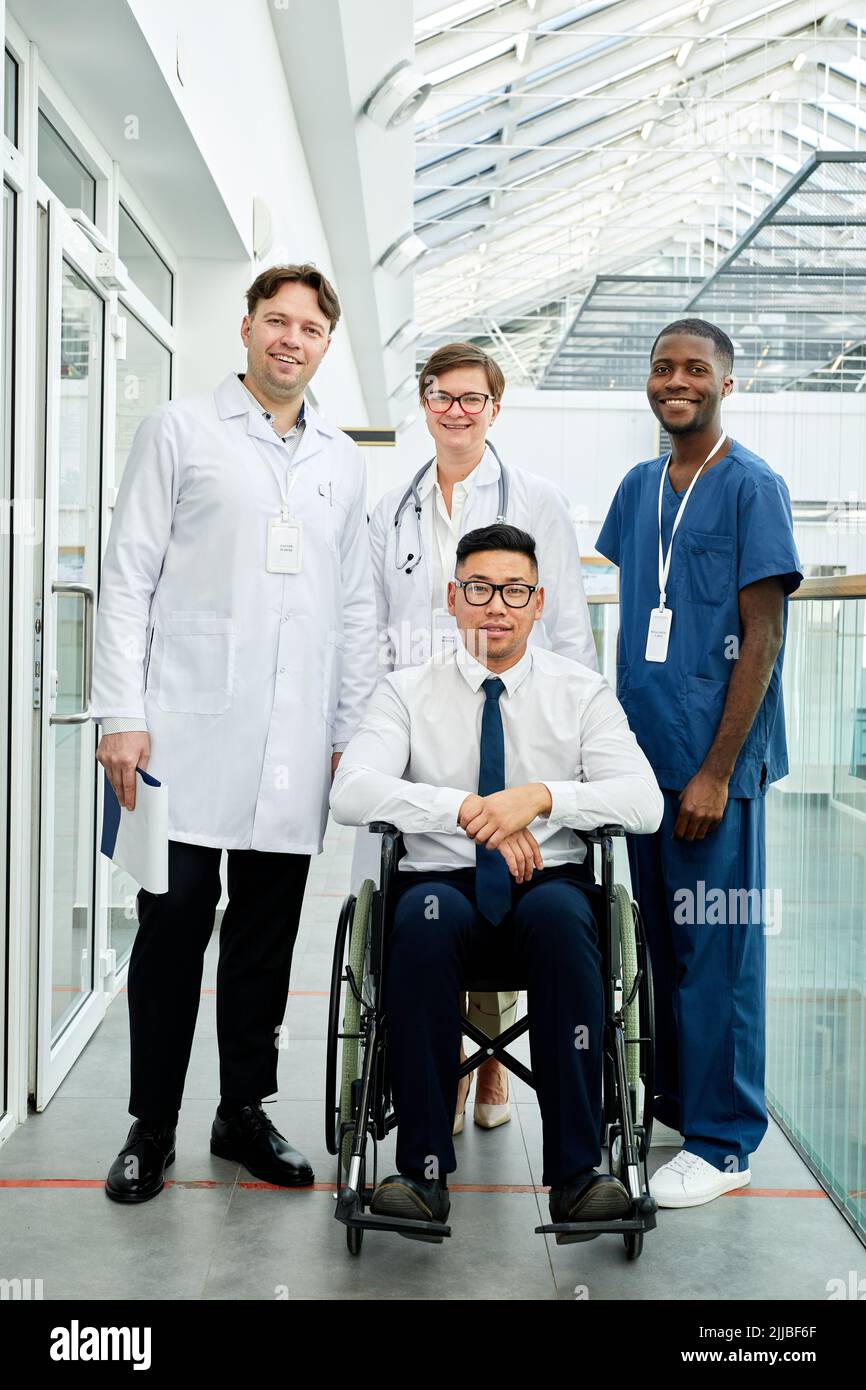 Full length portrait diverse group of doctors posing with patient in ...
