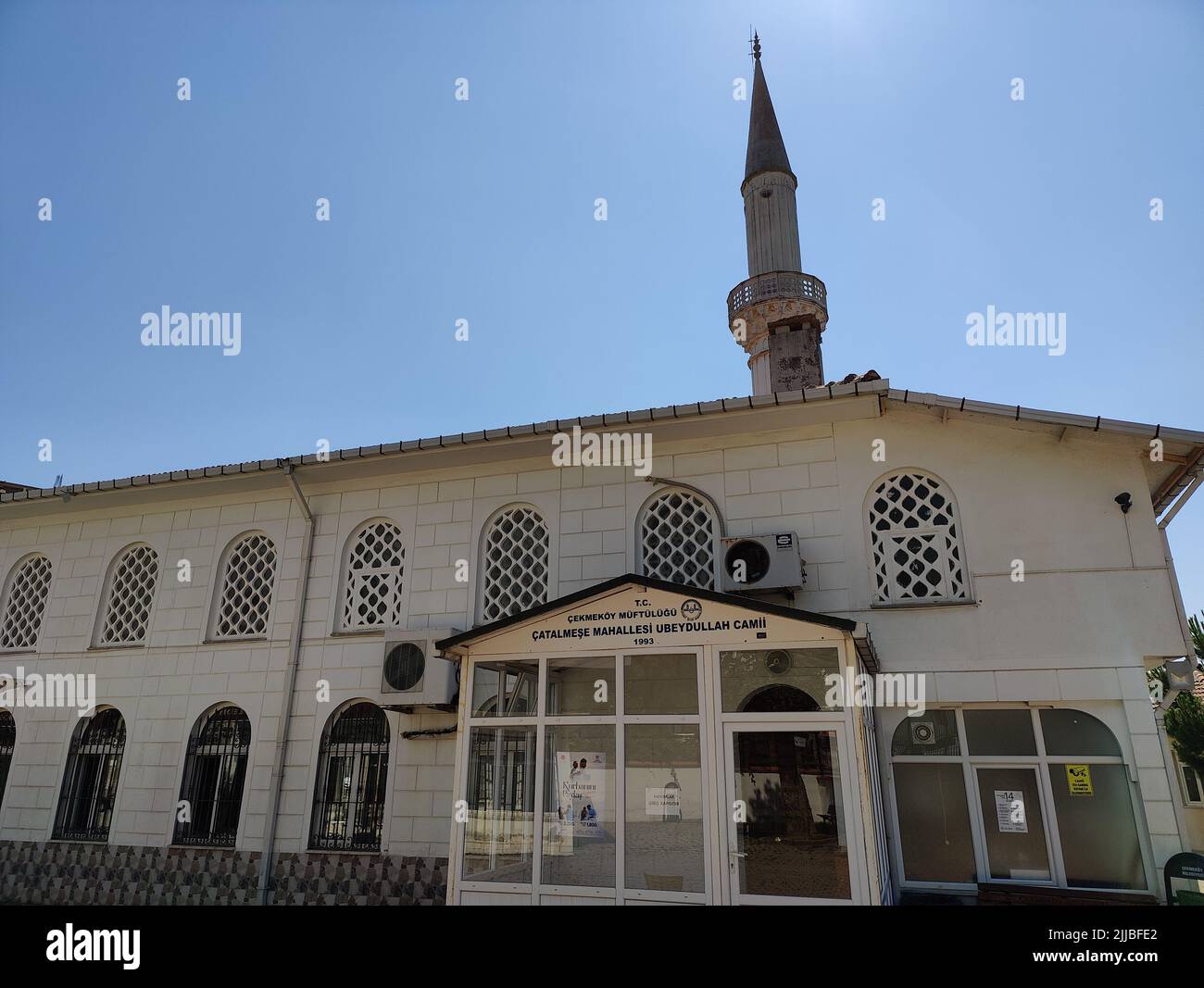 White Facade Building with Arched Windows and Minaret Under Clear Blue ...
