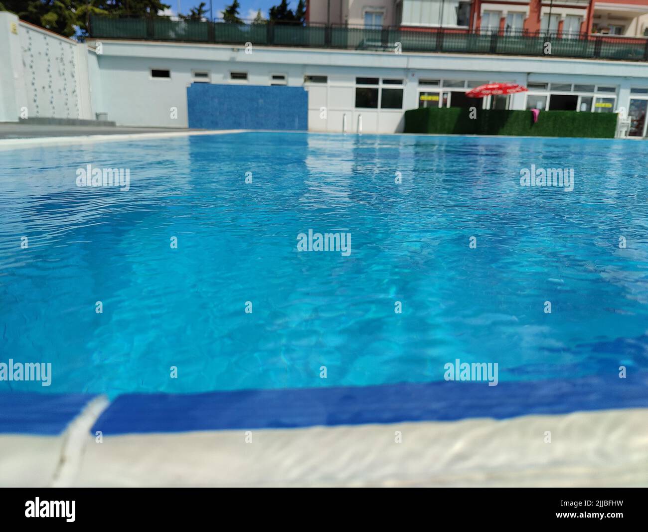 Rectangular Outdoor Pool with Clear Blue Water and Red Umbrella on a ...