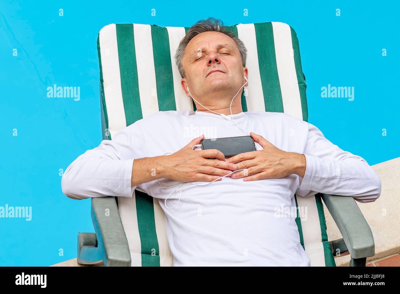 A middle-aged white man relaxes by listening to music with headphones ...
