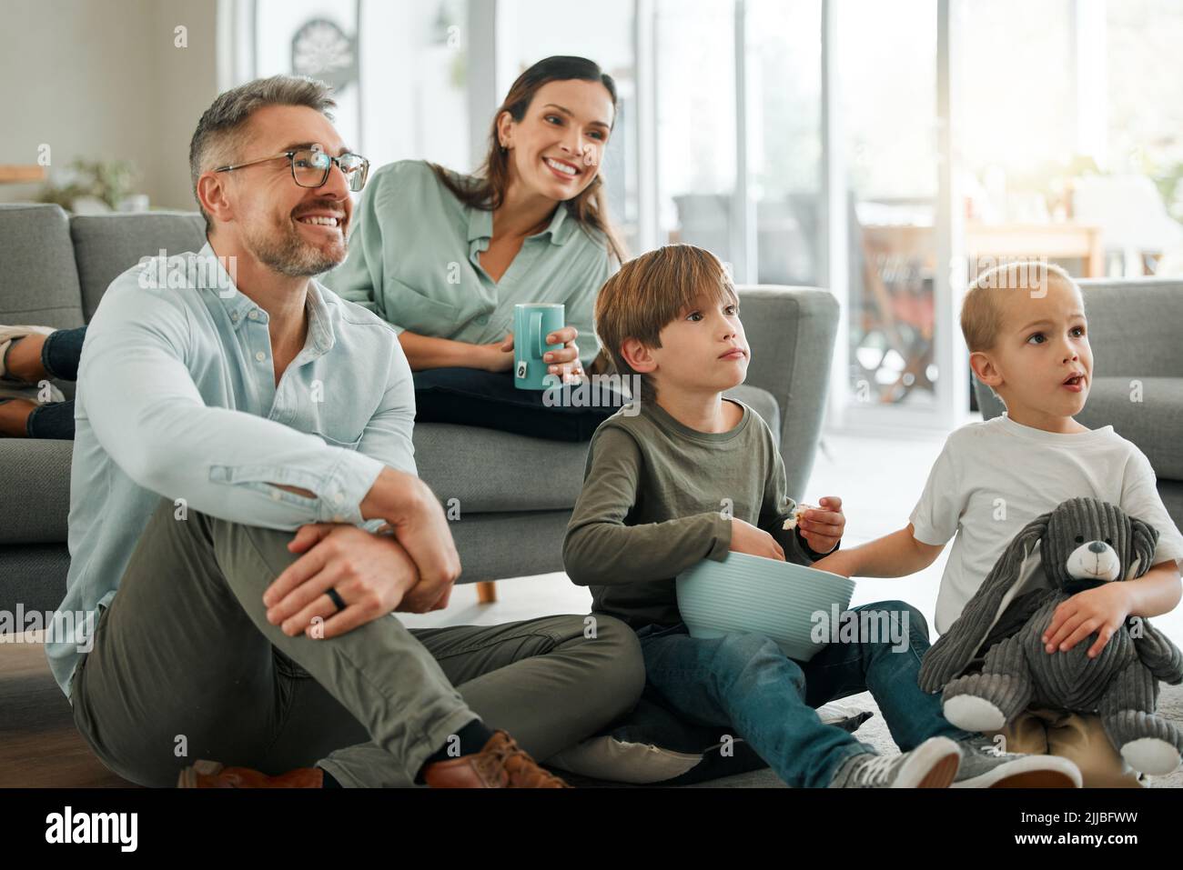 Weekends are for family time. a young family watching tv together at ...
