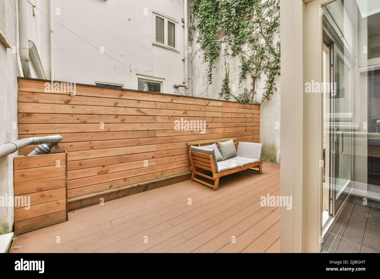 Neat paved patio with sitting area near wooden fence Stock Photo - Alamy