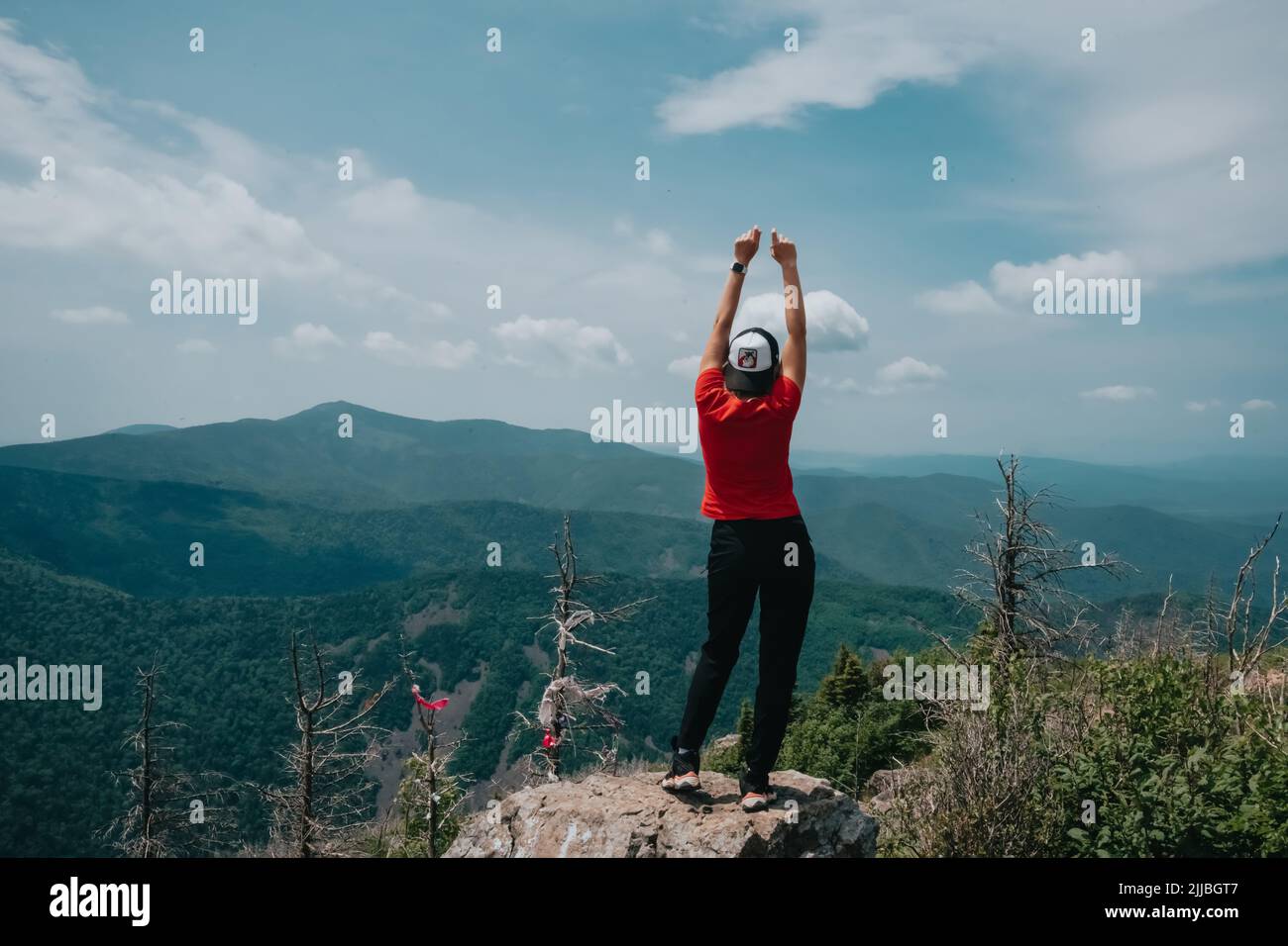 A girl on top of Falaza mountain looks at a beautiful mountain valley ...