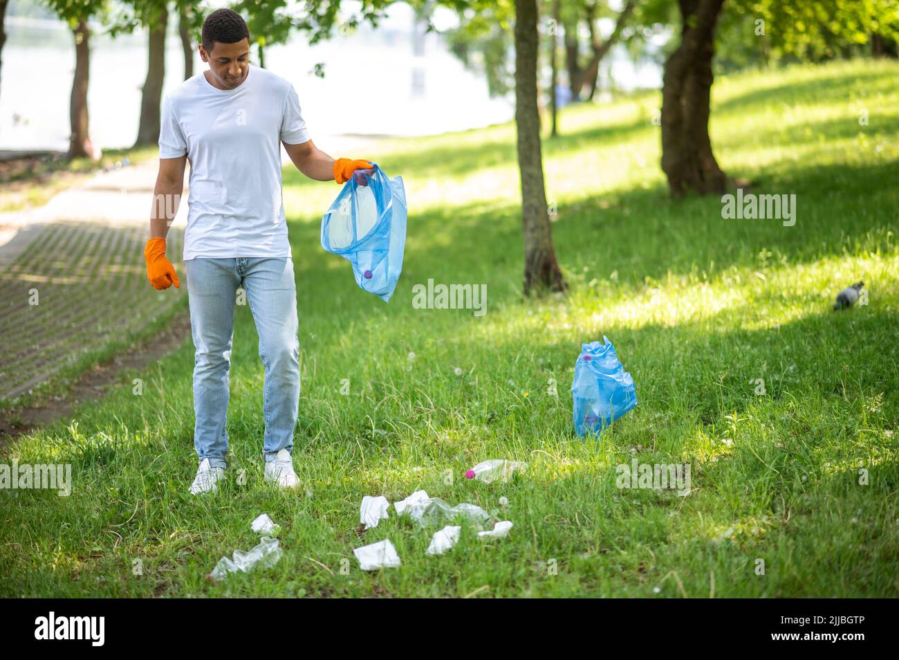 Man standing looking at garbage on grass Stock Photo - Alamy