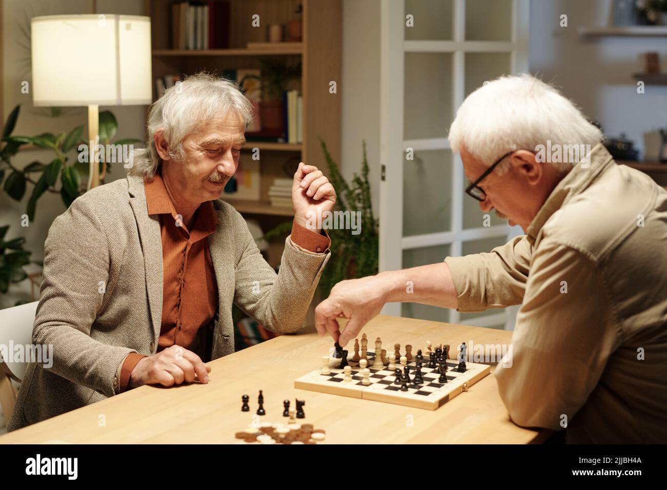 Happy senior man looking at his buddy moving black figure along ...