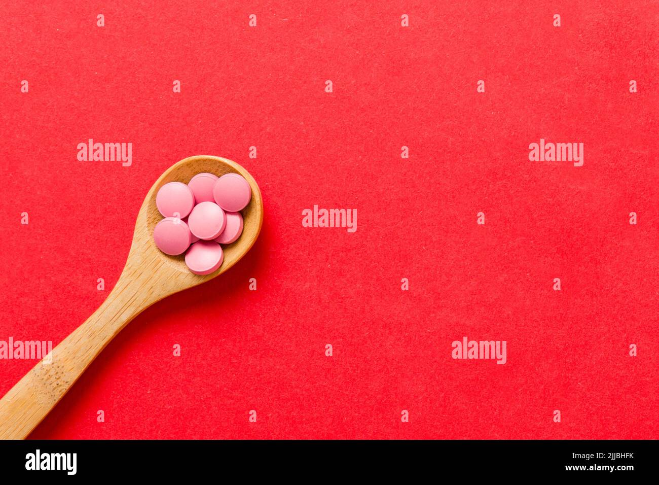 Vitamin capsules in a spoon on a colored background. Pills served as a ...