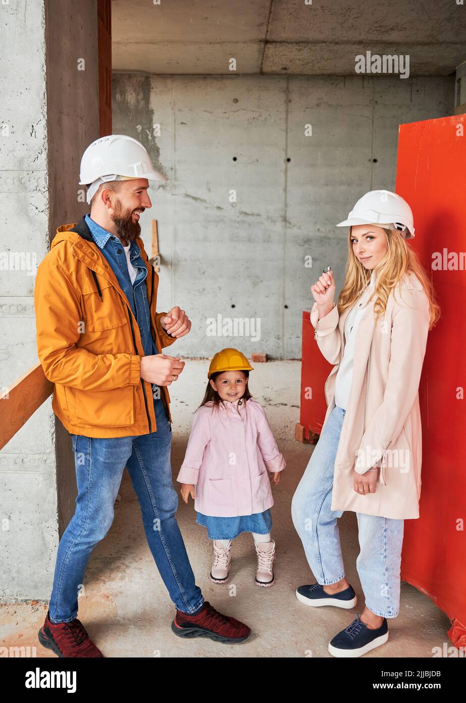 Man giving apartment keys to wife while little girl looking to the camera. Parents with daughter ...