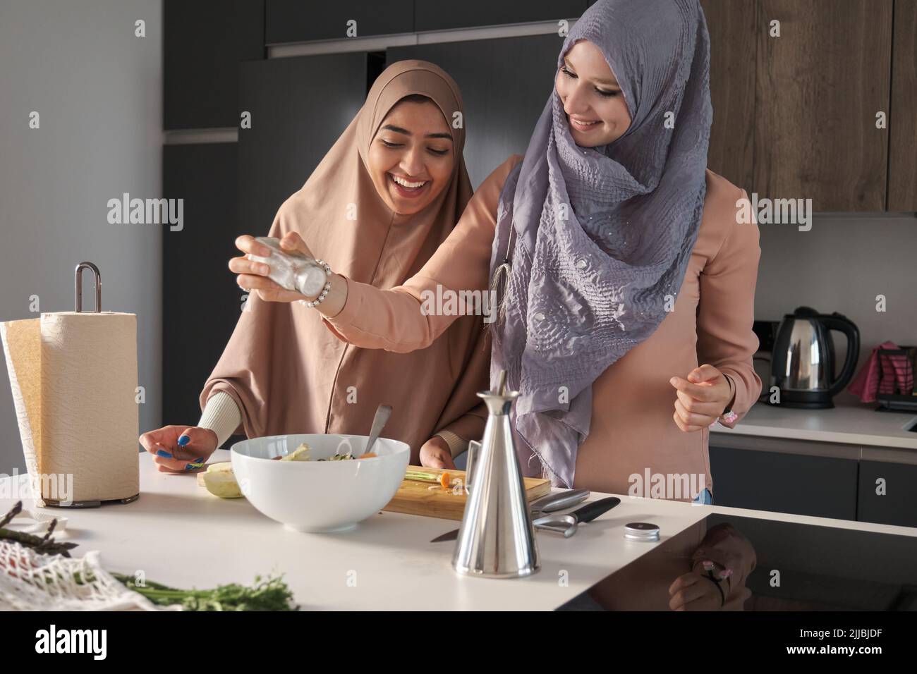 Two muslim women preparing a salad at modern kitchen Stock Photo - Alamy