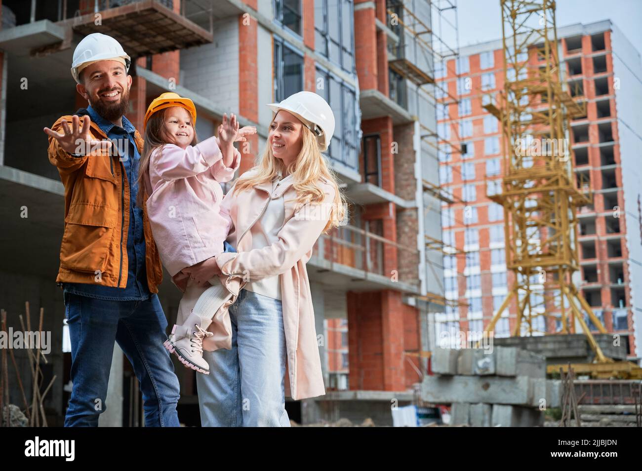 Man, woman and child standing outside building under construction ...