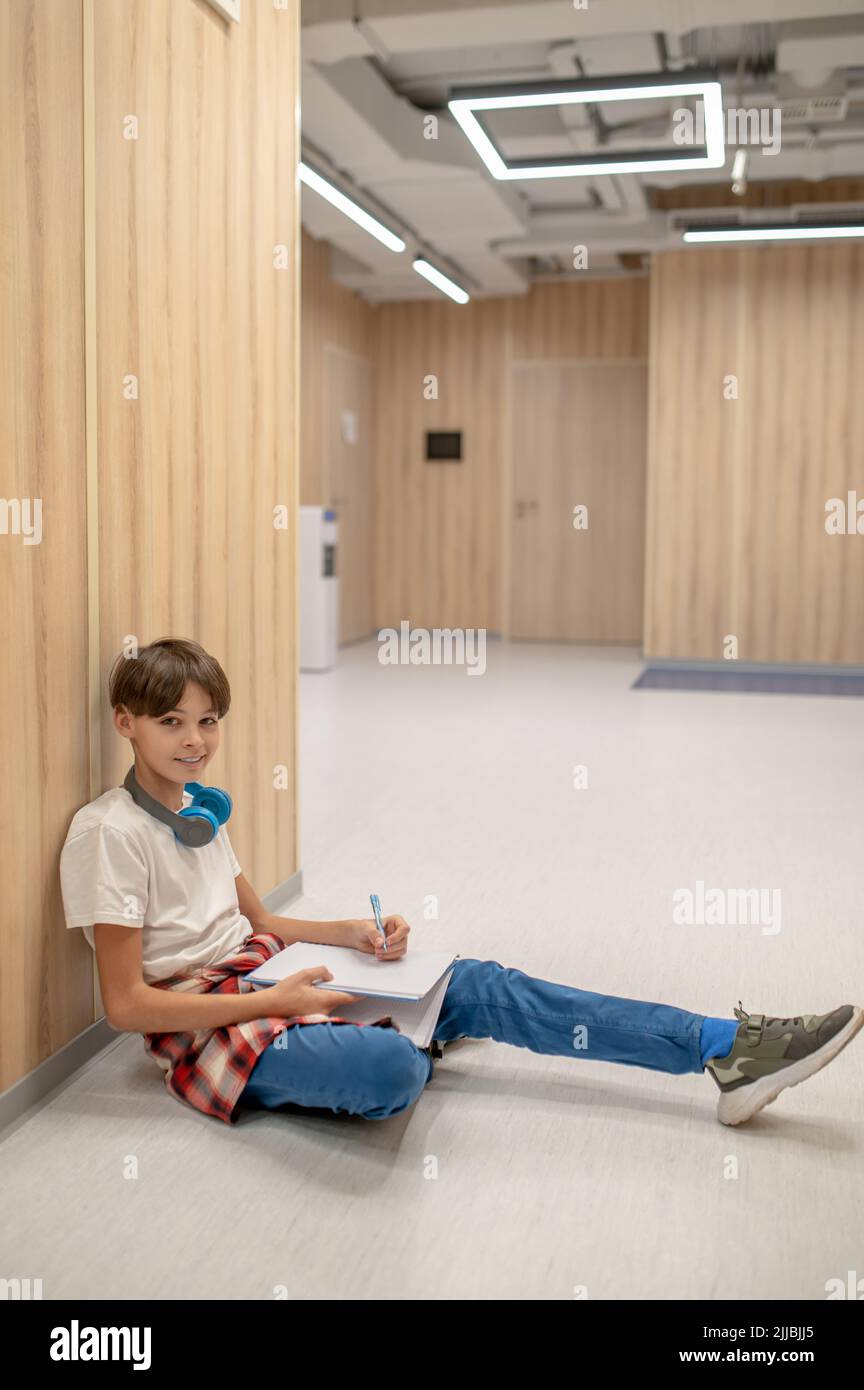 A boy sitting on the floor and doing his homework Stock Photo - Alamy