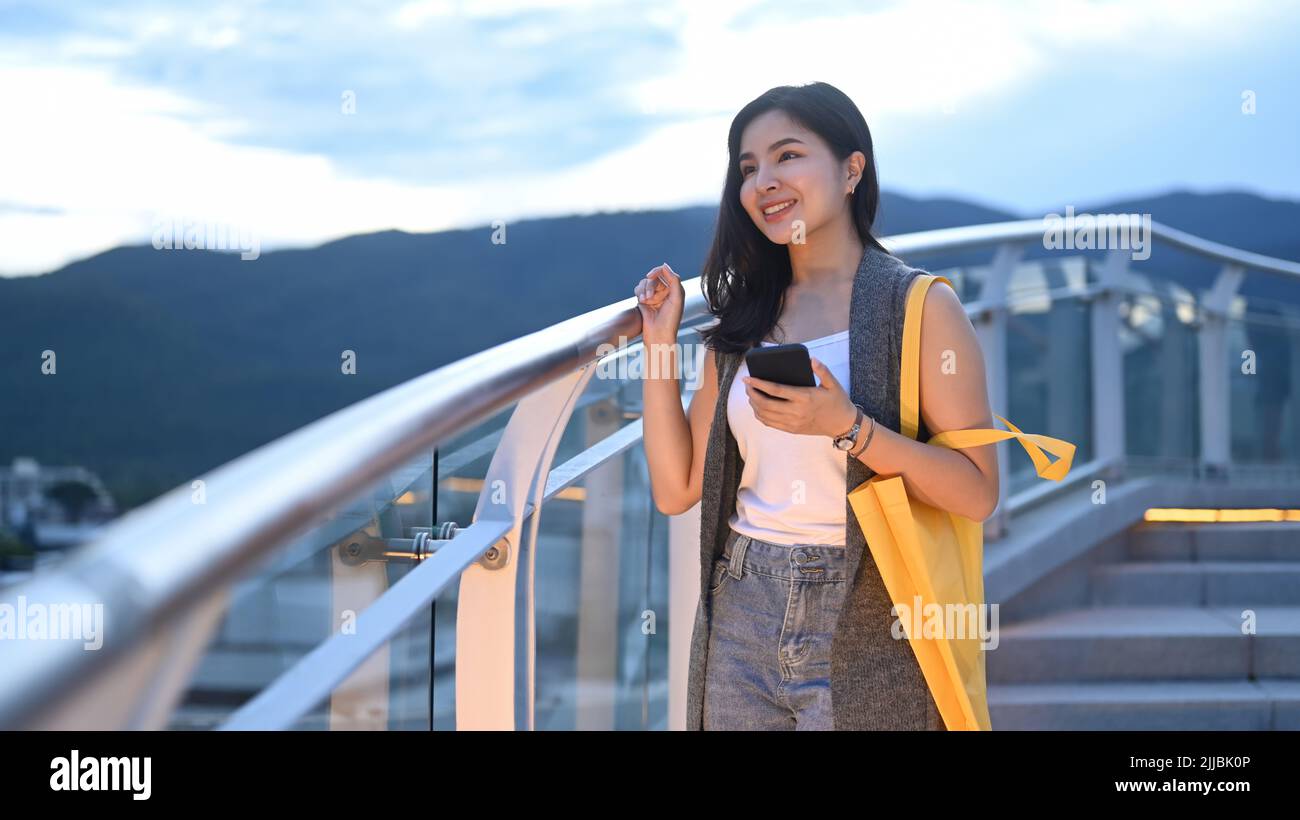 Happy stylish asian woman standing on rooftop terrace with beautiful ...