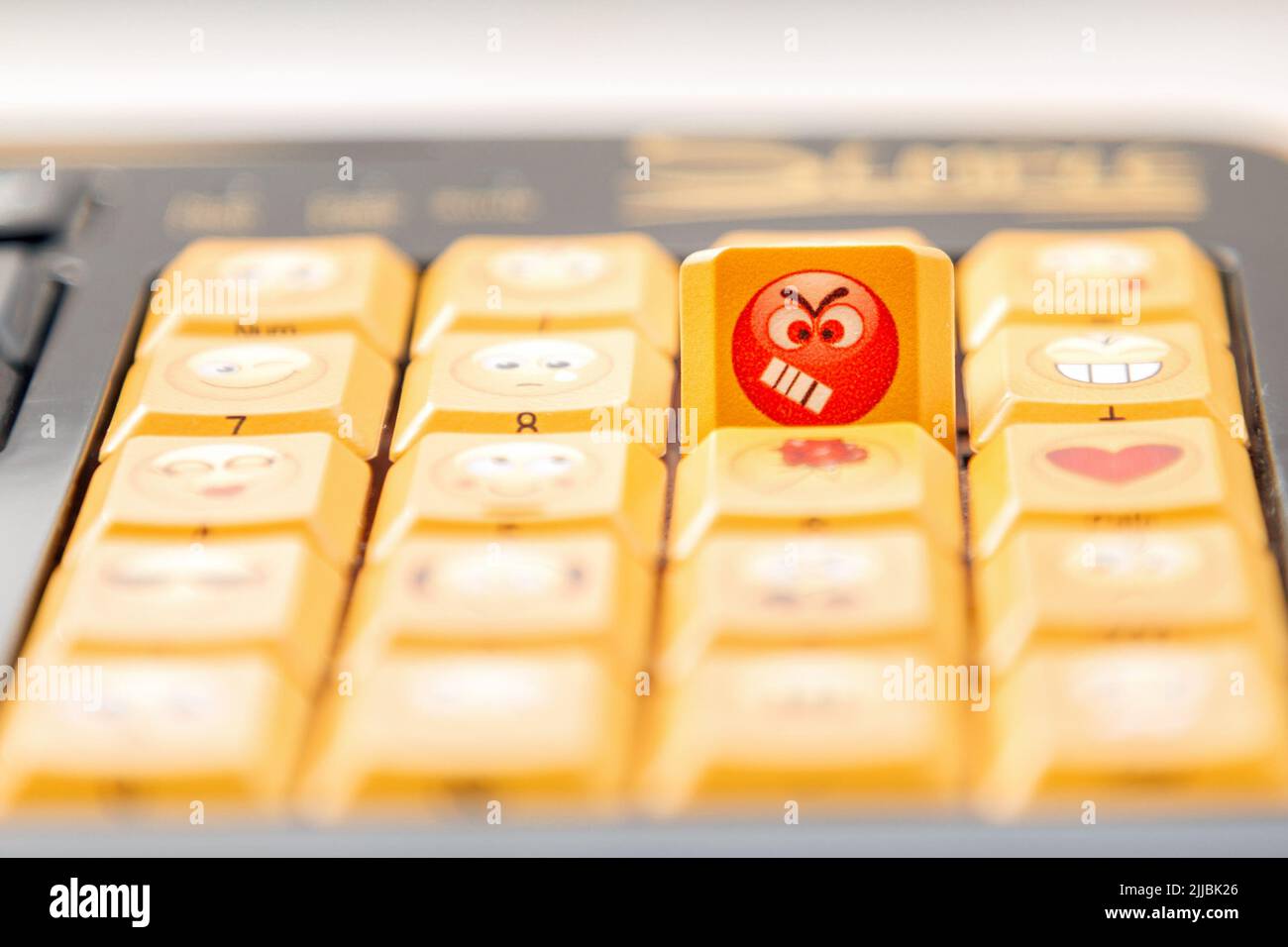Keyboard with a protruding button with an angry smiley face. Close up ...