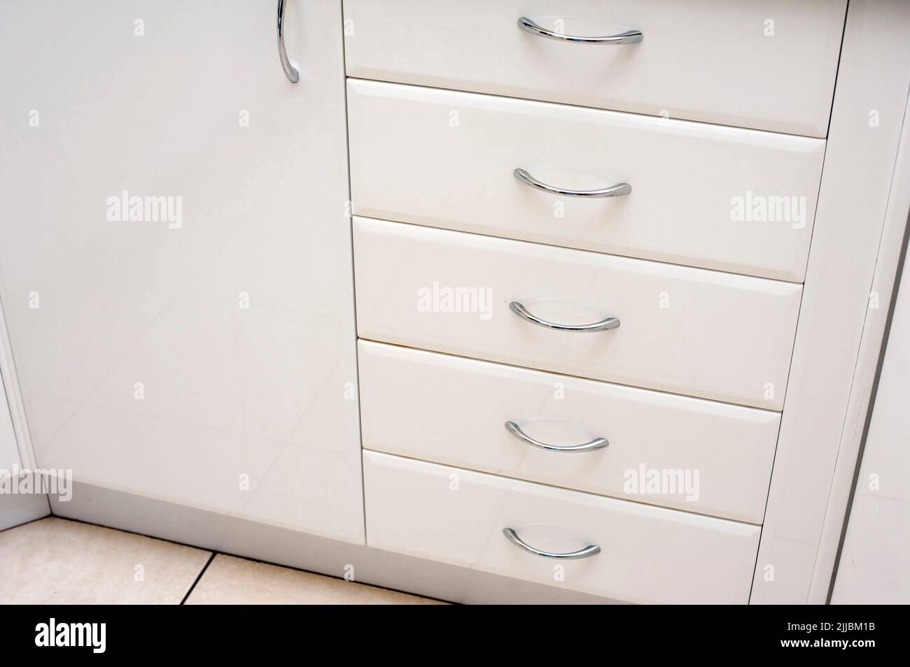 White kitchen cabinet with a row of closed drawers and a cupboard door ...