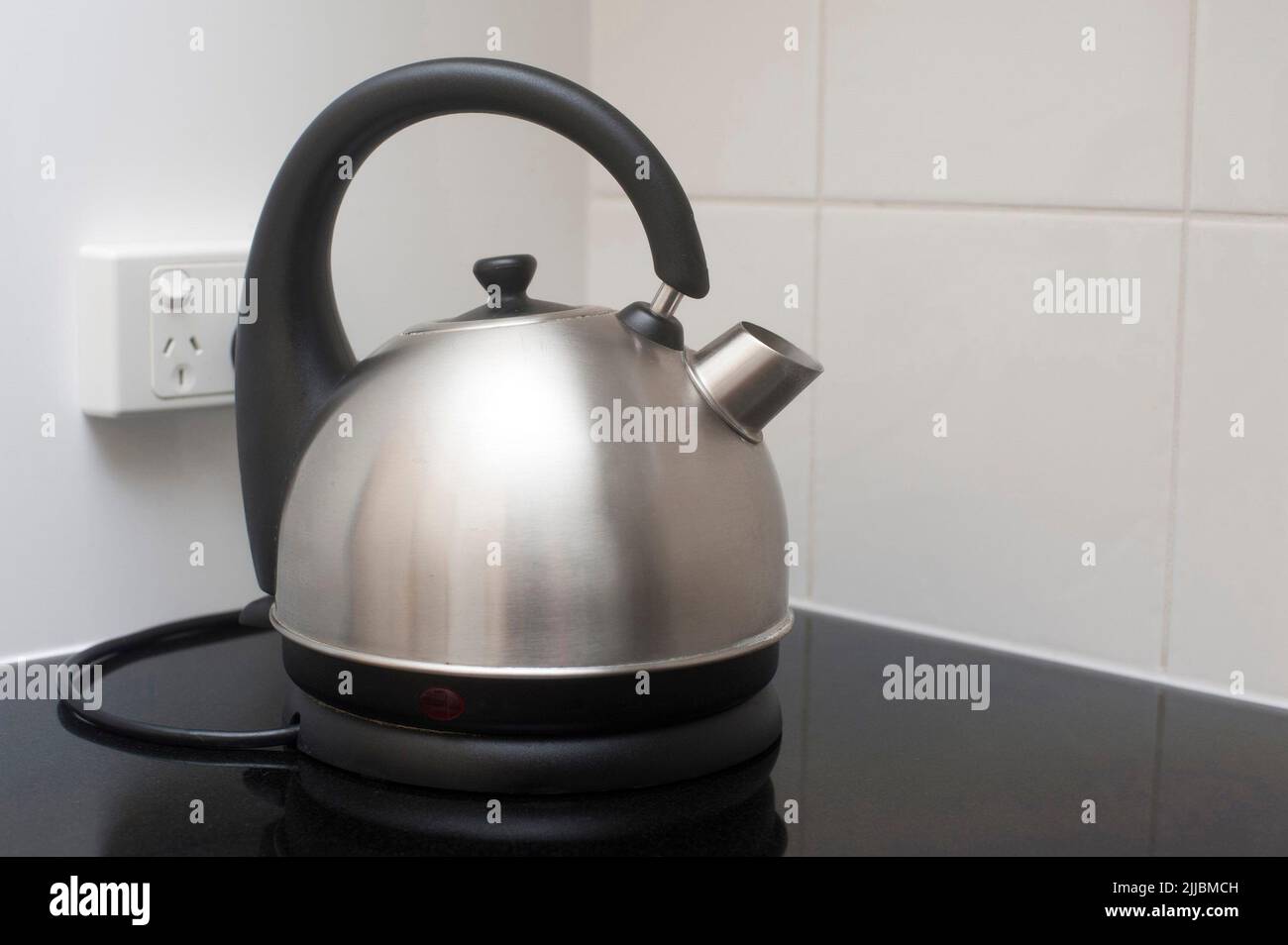 Modern silver metal cordless domed domestic kettle standing on its base ...