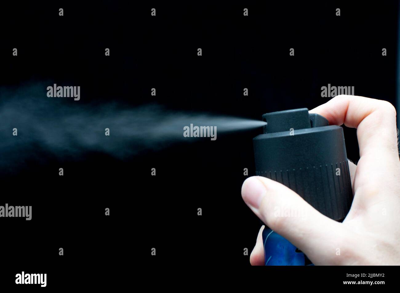 spraying a can of deodorant on a black background Stock Photo - Alamy