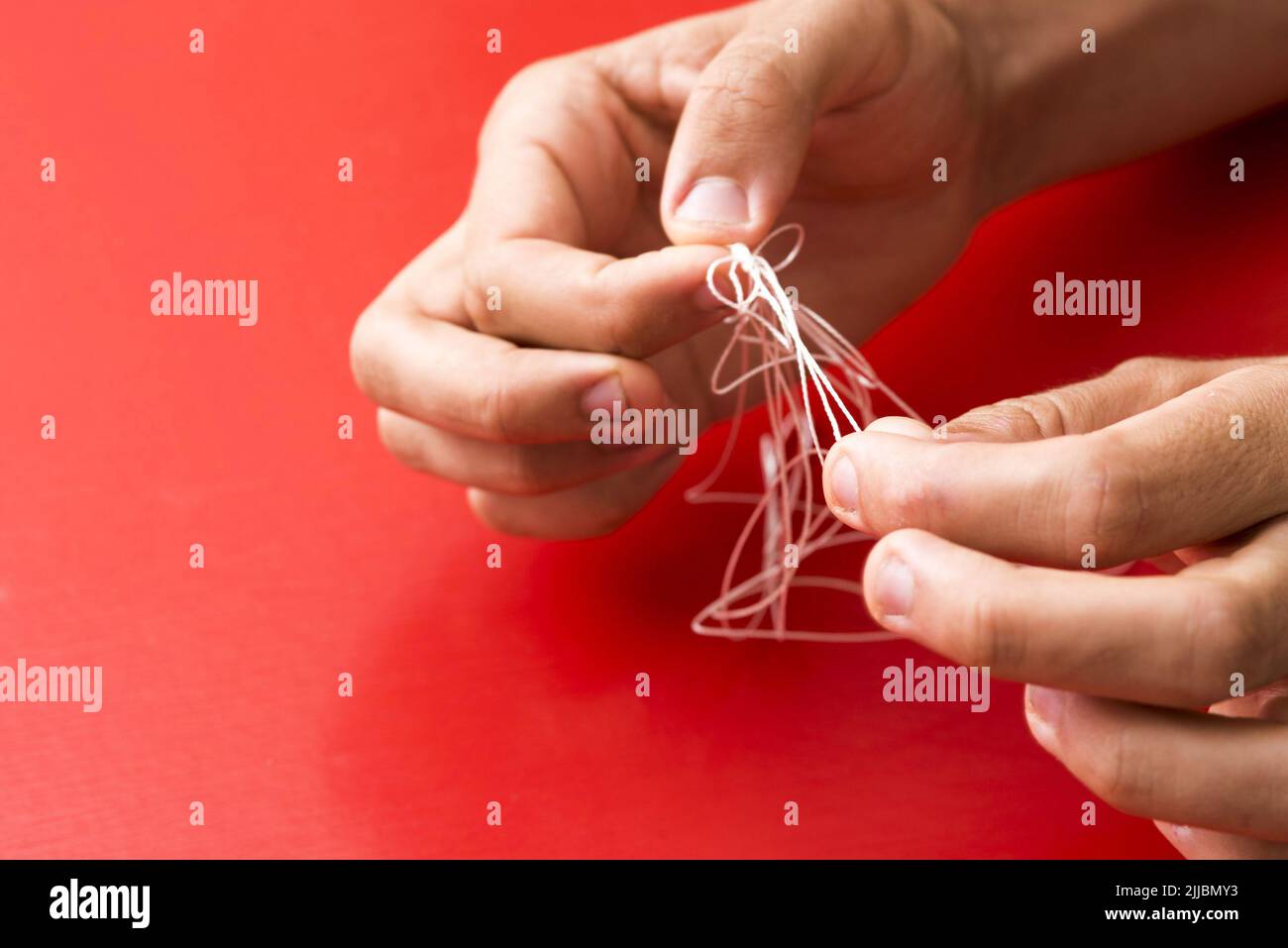 Working on Problem concept with the hands of a man untangling a knot in ...