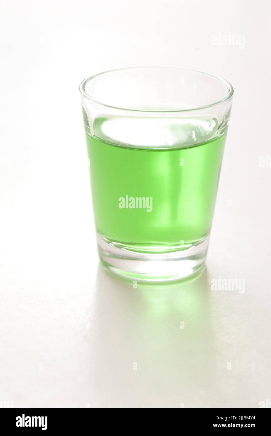 Shot glass of green absinthe, a potent alcoholic spirit with a taste of ...