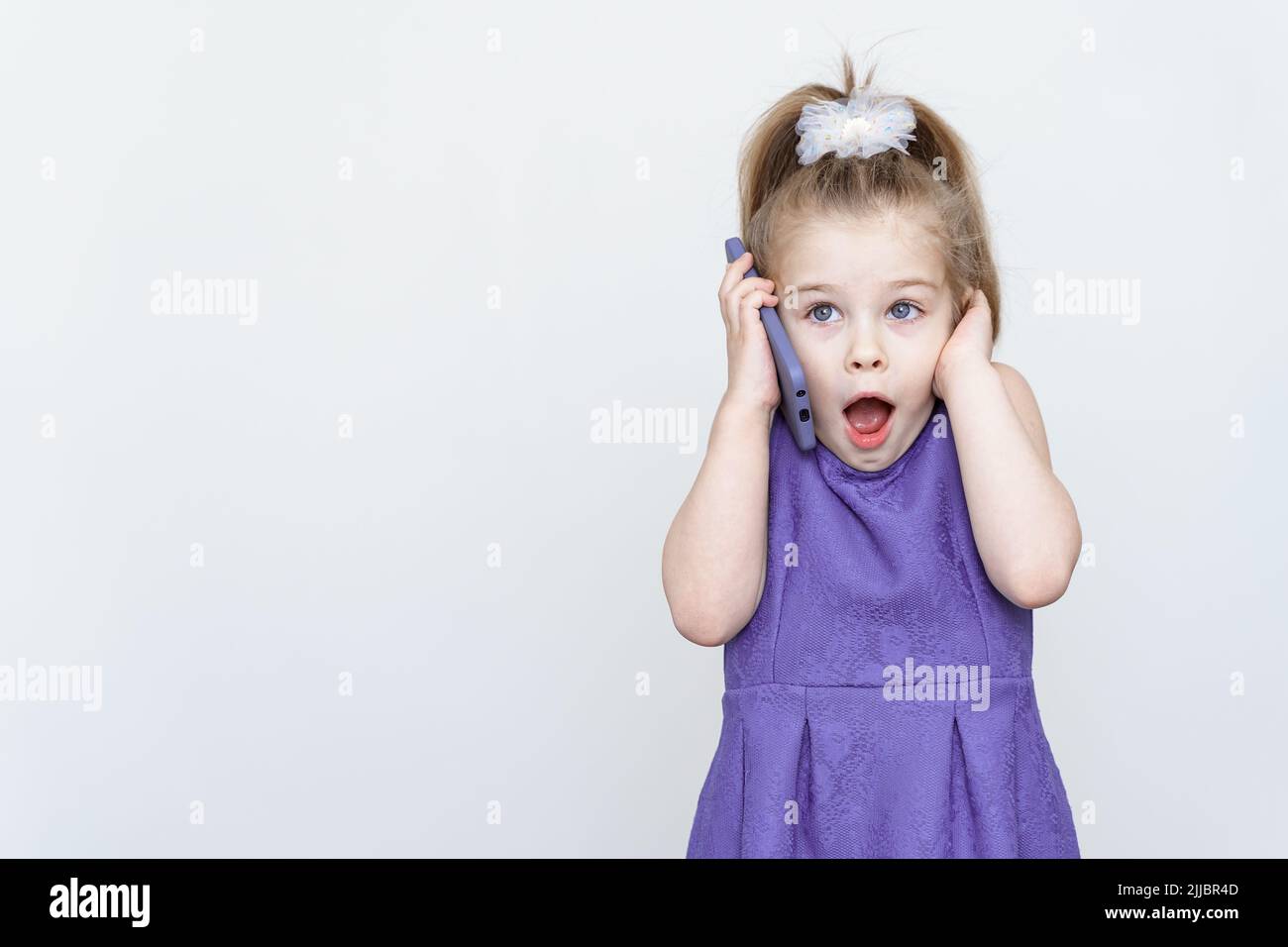 surprised and shocked little girl talking on the phone. place for text ...