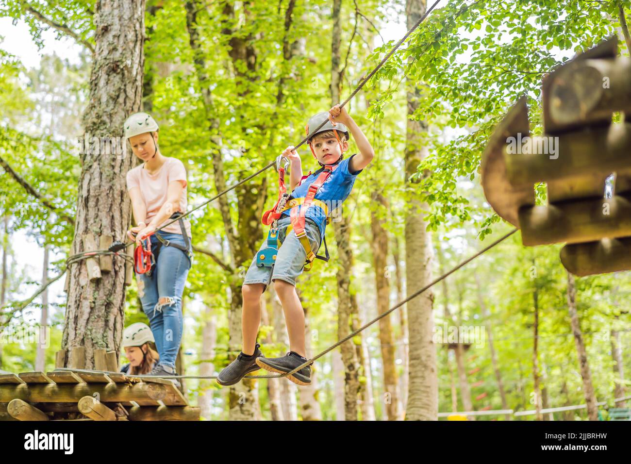 Mother and son climbing in extreme road trolley zipline in forest on ...